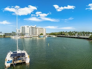 Uma marina com barcos, um edifício grande ao fundo e um céu claro.
