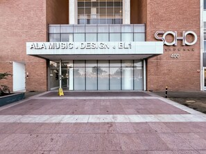 Entrada de um edifício com uma placa indicando 'ALAMUSIC DESIGN BL1' e 'SOHO SIDENCE 400'.