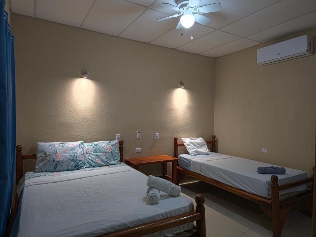 Quarto com duas camas de solteiro, ventilador de teto e ar condicionado.
