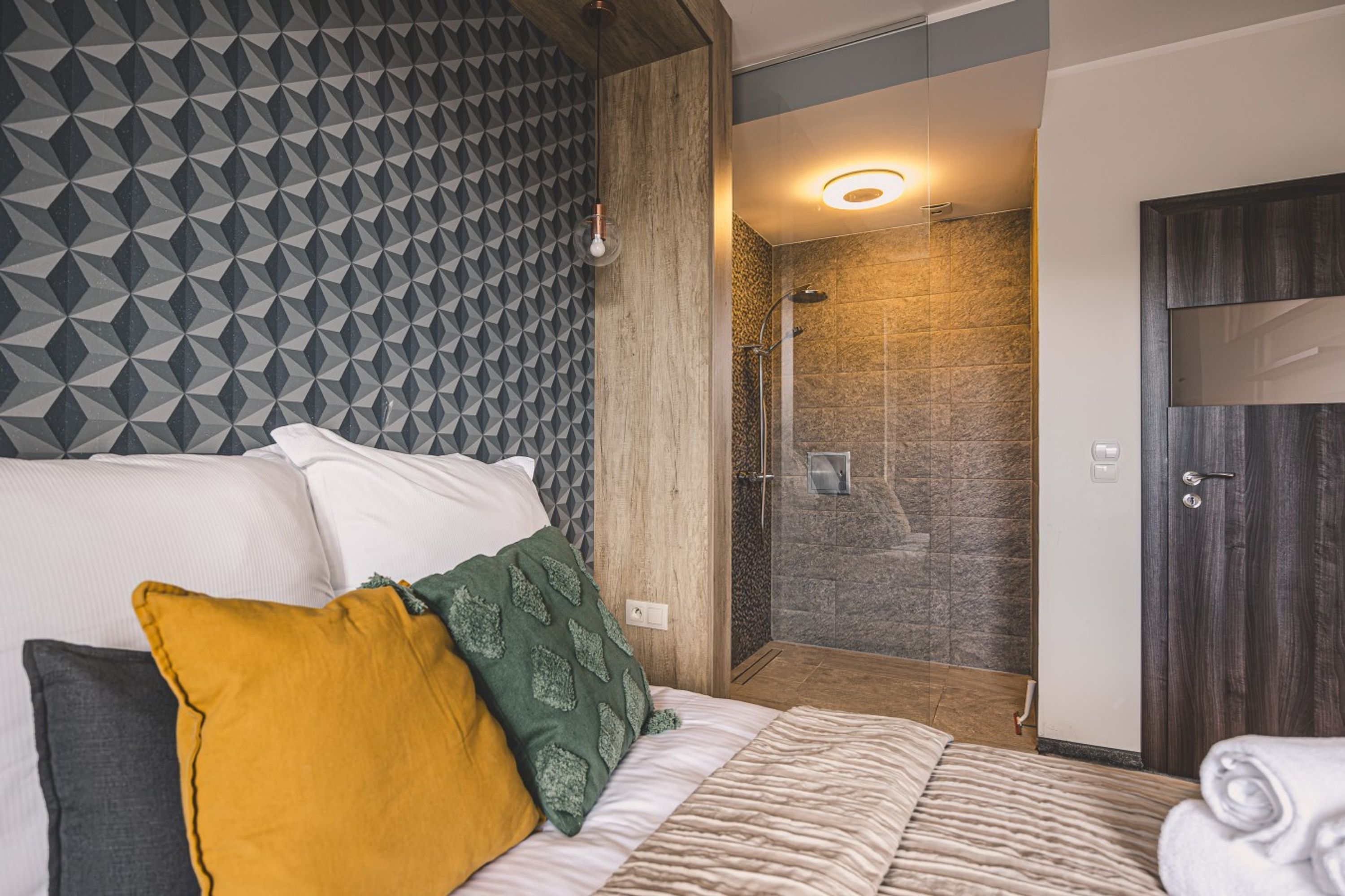 Quarto de hotel com cama, chuveiro e porta.