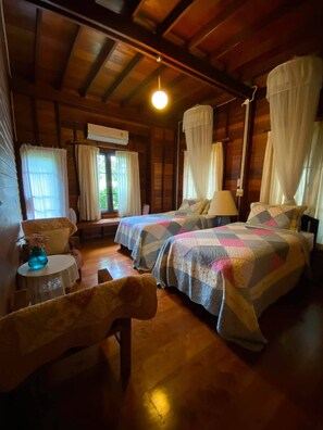 Uma cabana de madeira com duas camas, uma mesinha e uma cadeira.