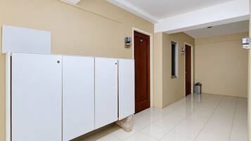 Um corredor com armários brancos, uma porta de madeira e uma lixeira.