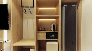 Cozinha compacta equipada com frigorífico, micro-ondas e armário pequeno.