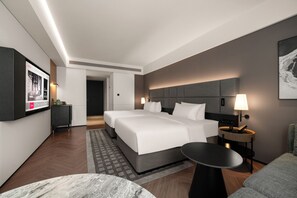 Quarto de hotel com uma cama grande, mesas de cabeceira, escrivaninha e televisão.