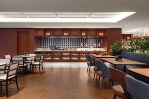 Restaurante moderno com área de bar, piso de madeira e diferentes disposições de assentos.
