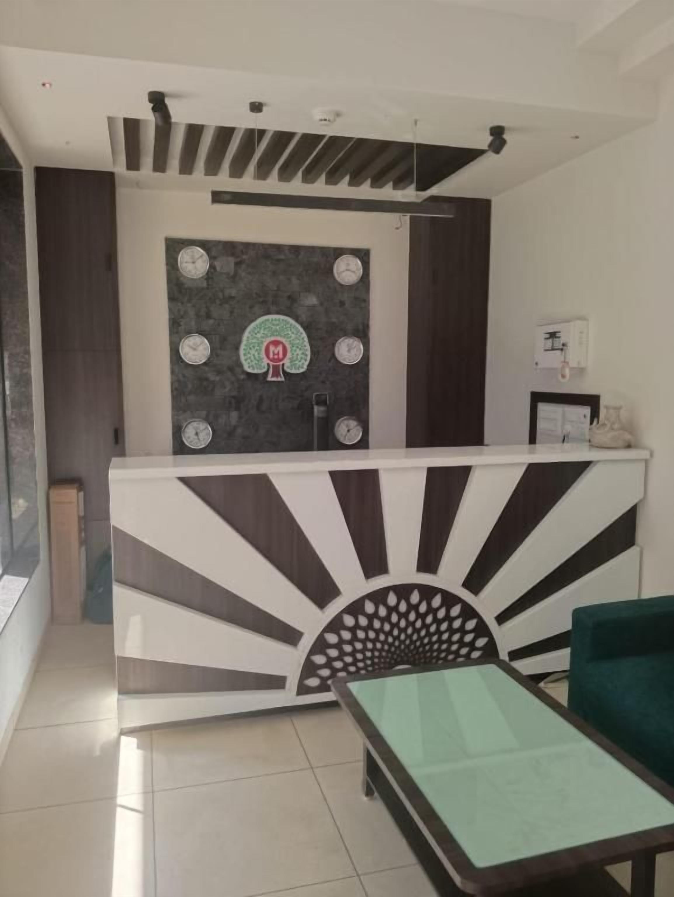 Uma área de recepção com design moderno, balcão de atendimento, espaço de espera com mesa e parede decorativa com relógios.