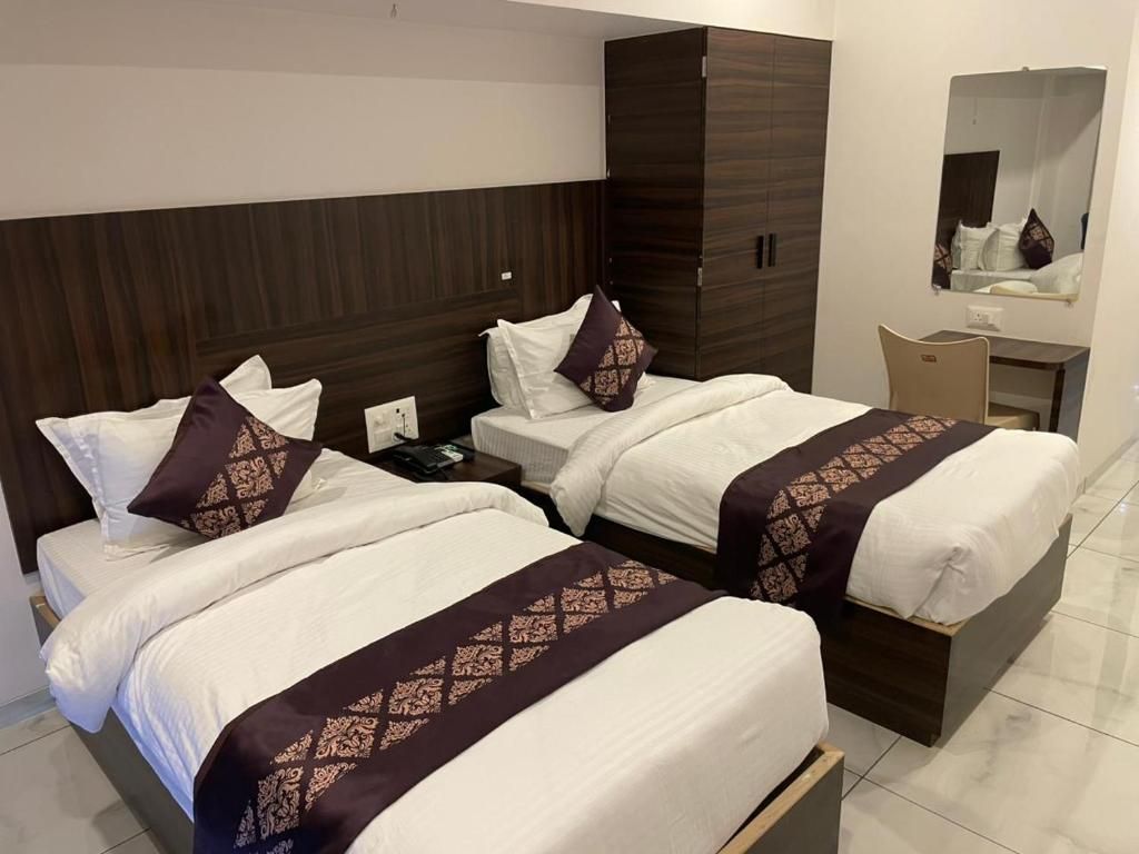 Quarto de hotel com duas camas, um guarda-roupa, uma escrivaninha e um espelho.