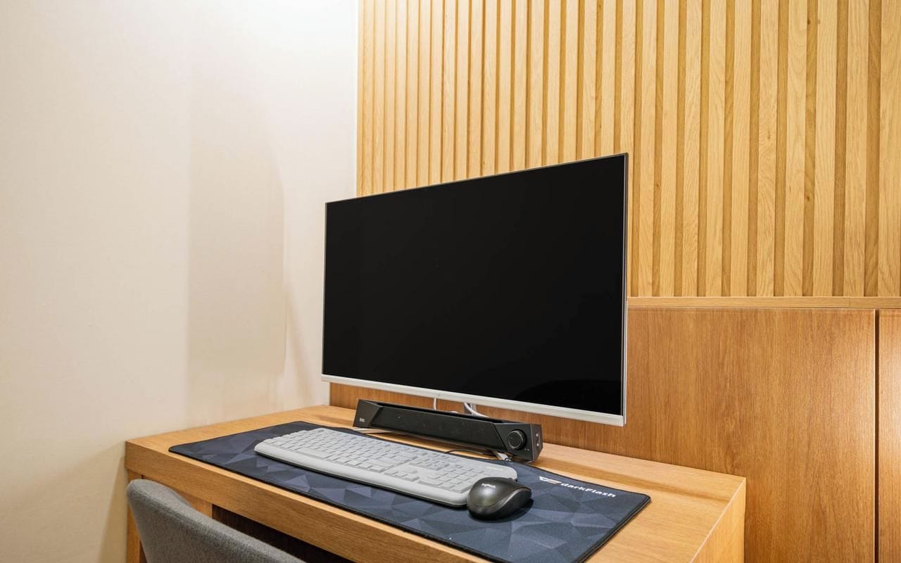 Uma mesa de computador com monitor, teclado, rato e apoio para rato.