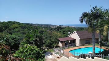 Um imóvel residencial com piscina, escadaria que leva a uma casa e vista para a área costeira.