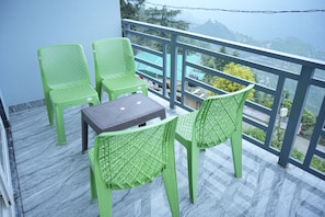 Uma varanda com uma mesa e quatro cadeiras verdes.