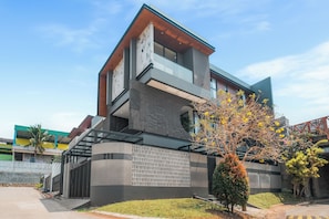 Um edifício moderno de vários andares com telhado plano, grandes janelas e uma combinação de materiais de pedra e concreto.