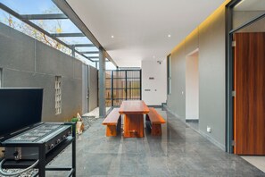 Decoração moderna com um longo corredor, uma mesa-banco de madeira e uma estação de churrasco.