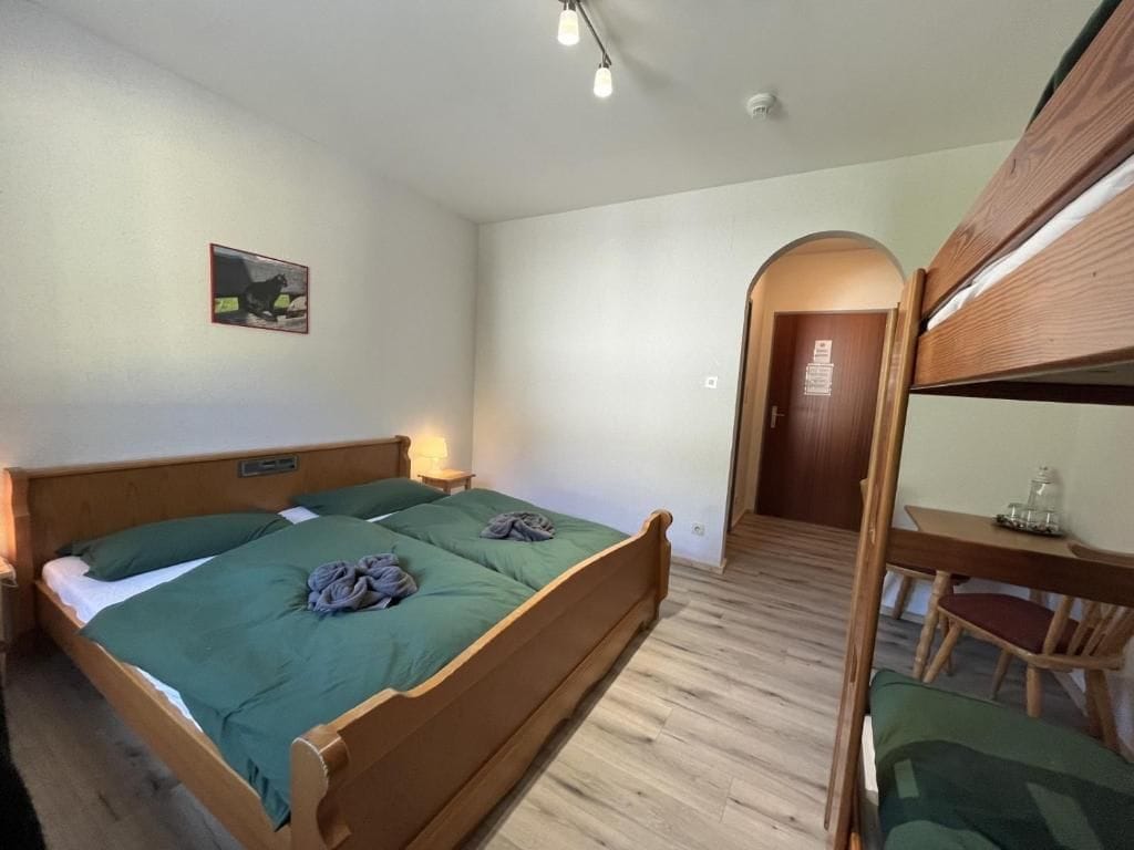 Quarto com cama de solteiro, uma cama individual, mesa de cabeceira, abajur e um quadro na parede.