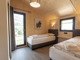 Quarto com duas camas, uma janela e porta para área externa.