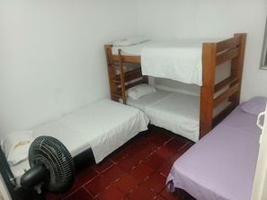 Quarto em dormitório com beliches, um ventilador e piso de azulejos.