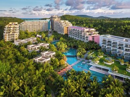 Resort com v ários edifícios, piscina central e vegetação exuberante.