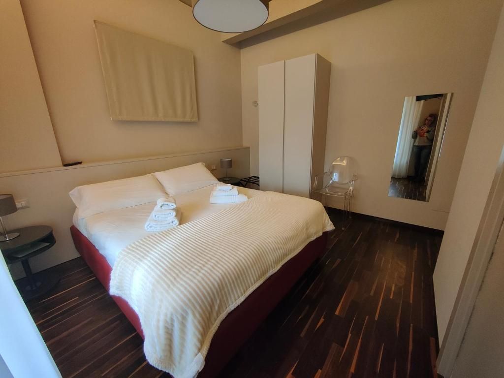 Quarto de hotel com cama, guarda-roupa, mesa de cabeceira e espelho.