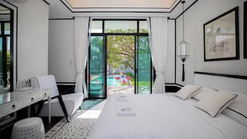 Quarto de hotel com cama, escrivaninha, cadeira e vista para uma piscina.