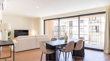 Uma sala de estar moderna com sofá, TV e área de jantar com cadeiras e mesa.