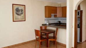 Uma cozinha compacta com armários de madeira, bancada de granito e mesa de jantar com cadeiras.