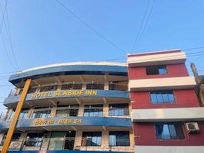Um edifício com vários andares, com uma placa indicando 'HOTEL SEASIDE INN' e outra placa em idioma diferente.