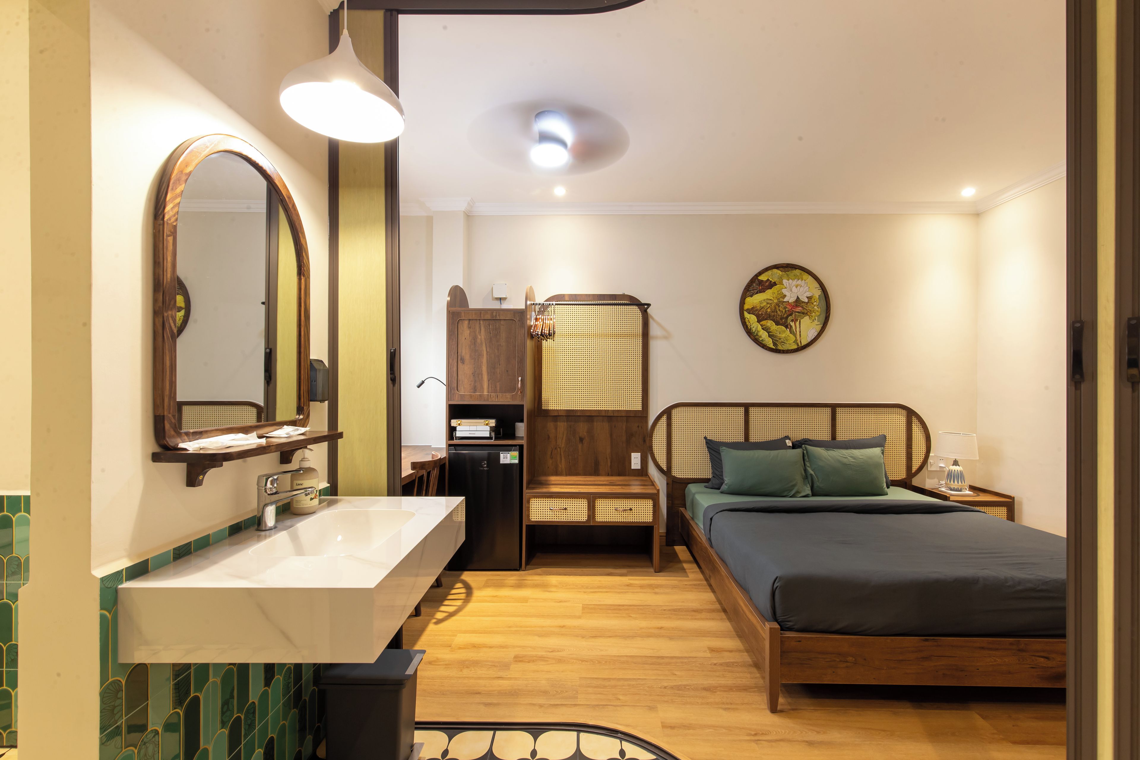 Quarto de hotel com cama de madeira, um espelho grande, pia e uma pequena mesa.