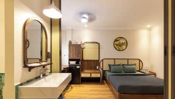 Quarto de hotel com cama de madeira, um espelho grande, pia e uma pequena mesa.