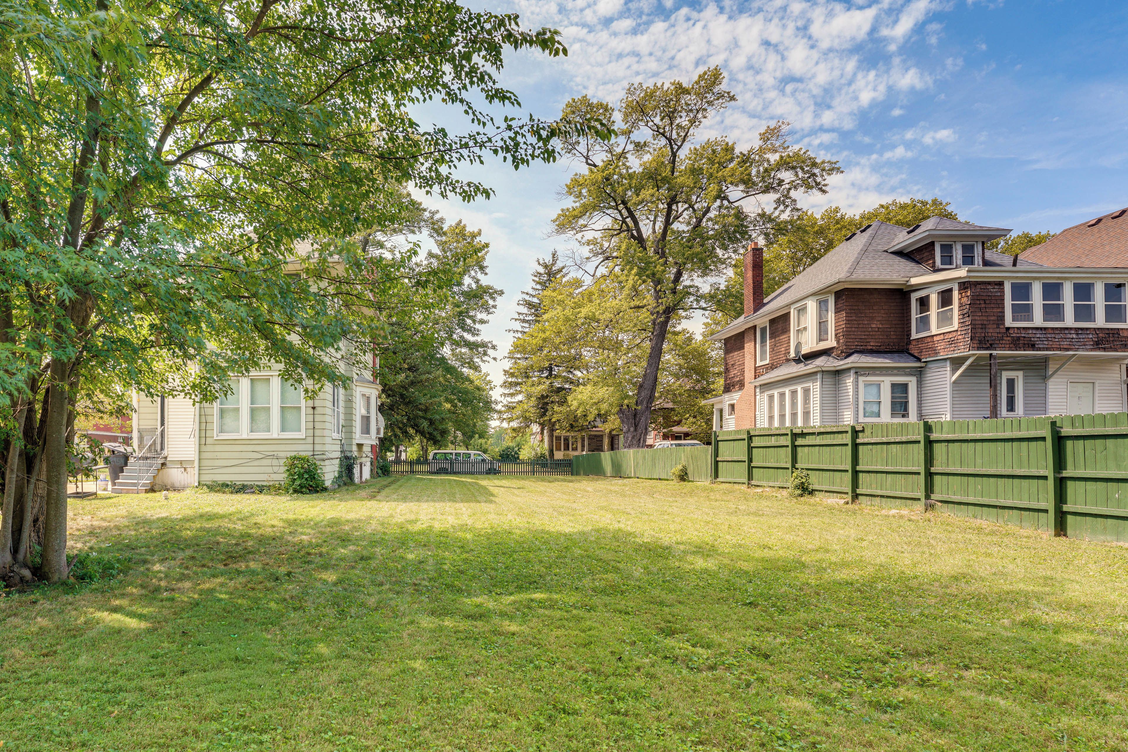 Um bairro residencial com casas, cerca verde e gramado.