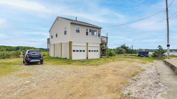 Uma casa de dois andares com garagem, um carro estacionado na frente e um caminho de terra.