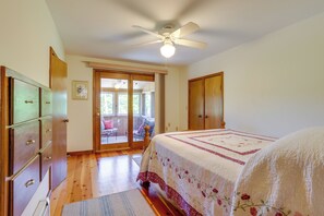 Quarto com cama, guarda-roupa de madeira e ventoinha no teto.