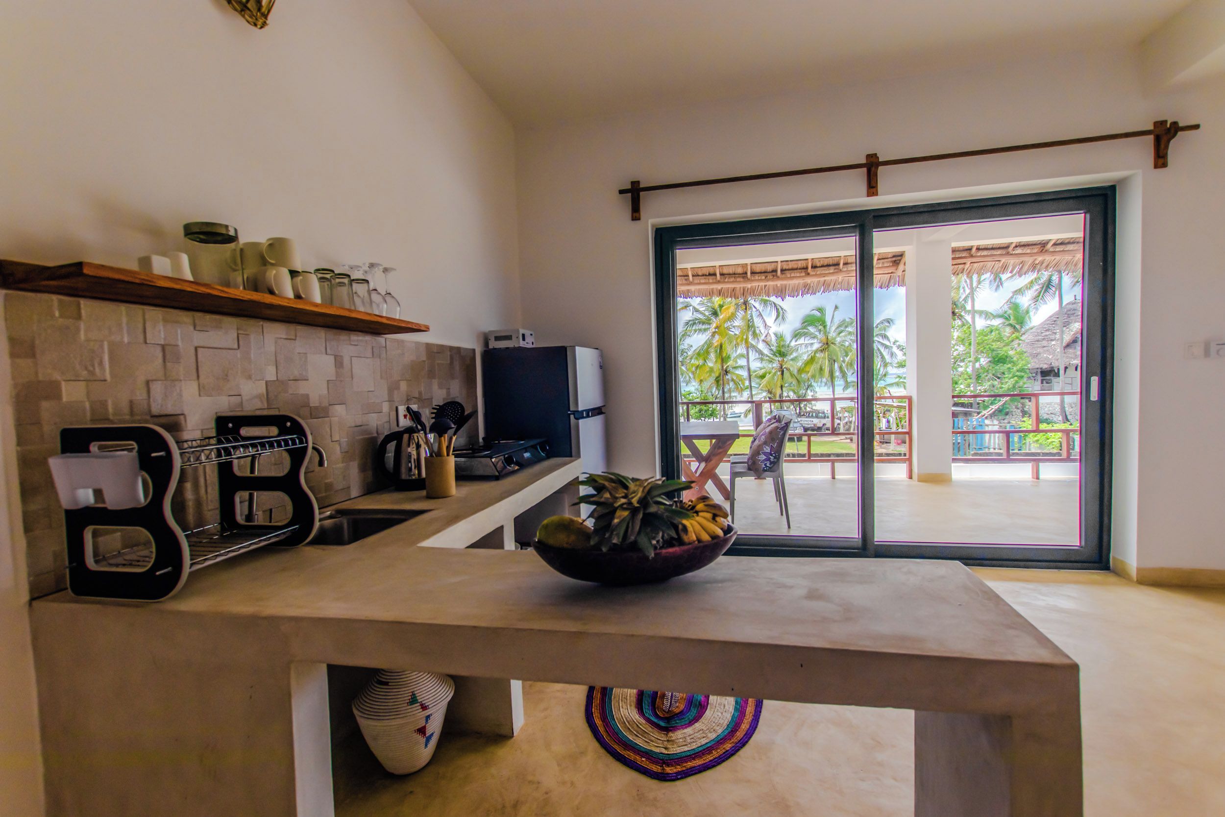 Cozinha moderna com área de jantar, televisão e vista para área tropical externa.