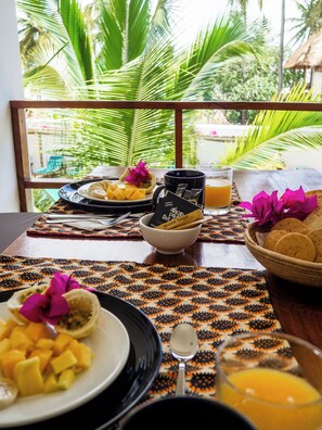 Uma mesa de café da manhã com pratos de comida, um pote de açúcar mascavo e um copo de suco de laranja.