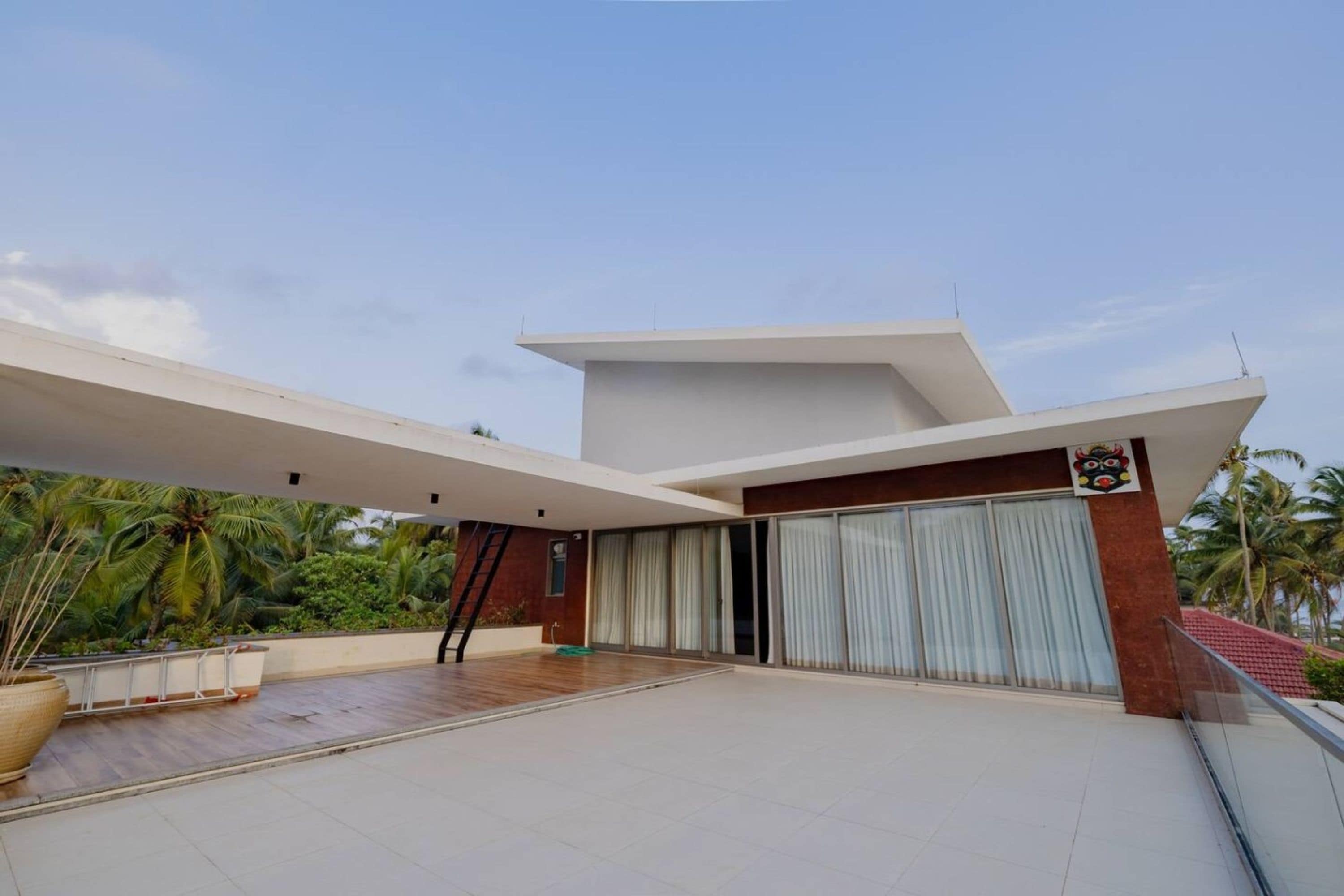 Uma casa moderna com telhado plano, amplas janelas e uma varanda.