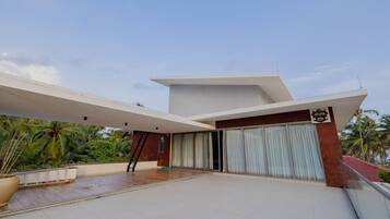 Uma casa moderna com telhado plano, amplas janelas e uma varanda.