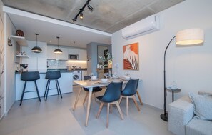 Cozinha moderna com área de refeições, banquetas de bar e mesa posta para dois.