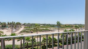 Varanda com vista para um canteiro de obras, palmeiras e um céu limpo.
