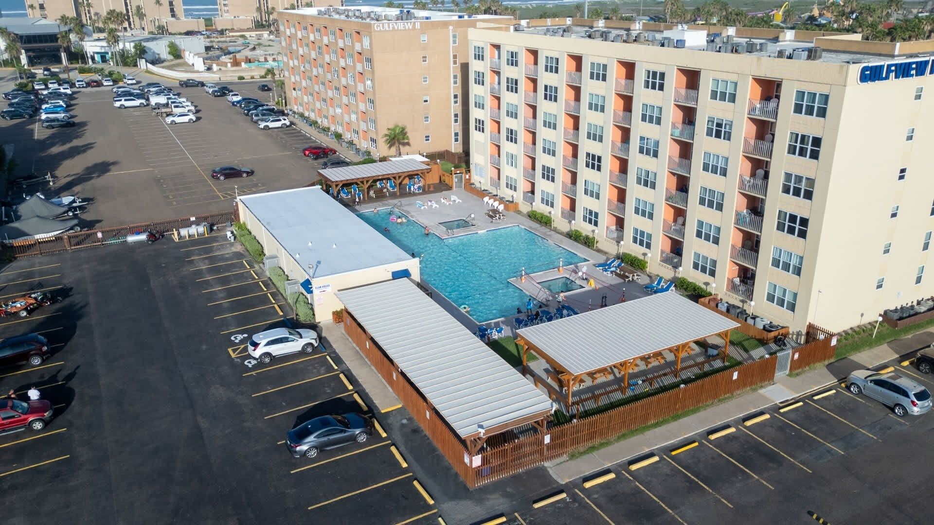 Um hotel com vários andares, piscina e estacionamento.