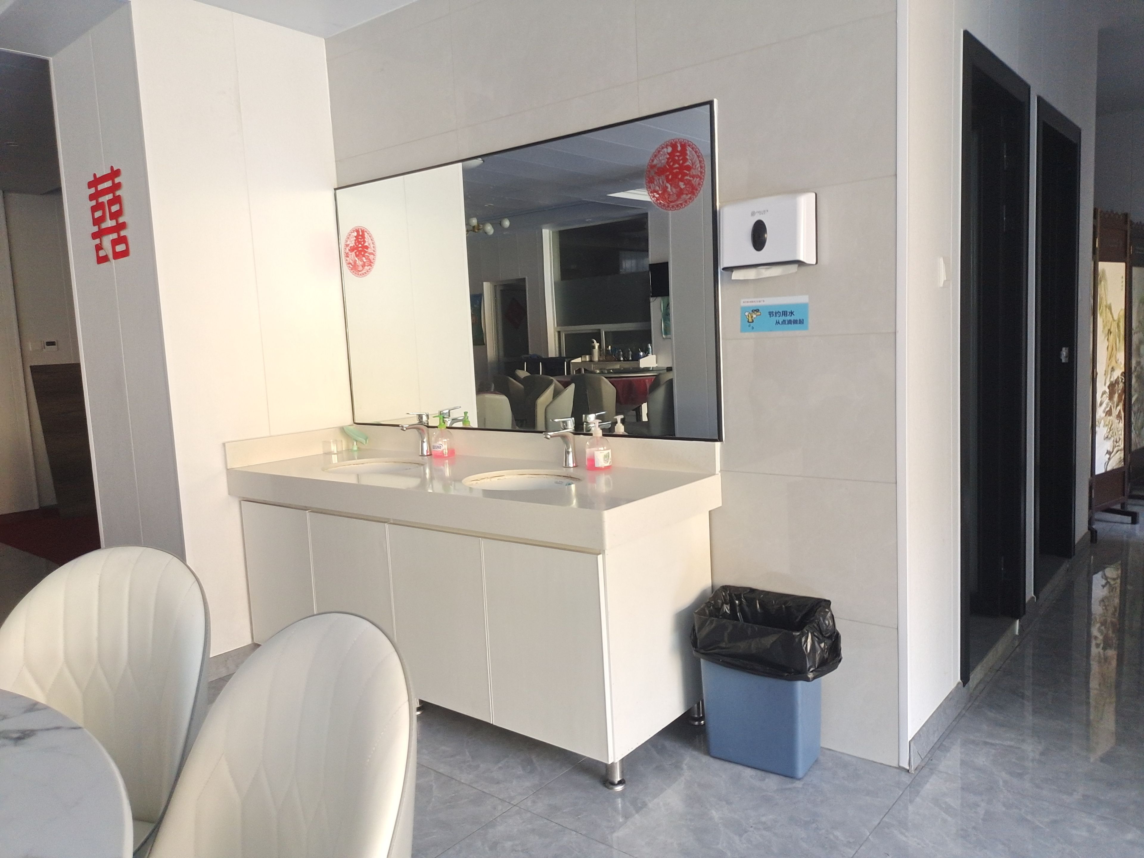 Casa de banho moderna com um espelho grande, duas lavatórios e um contentor de lixo.