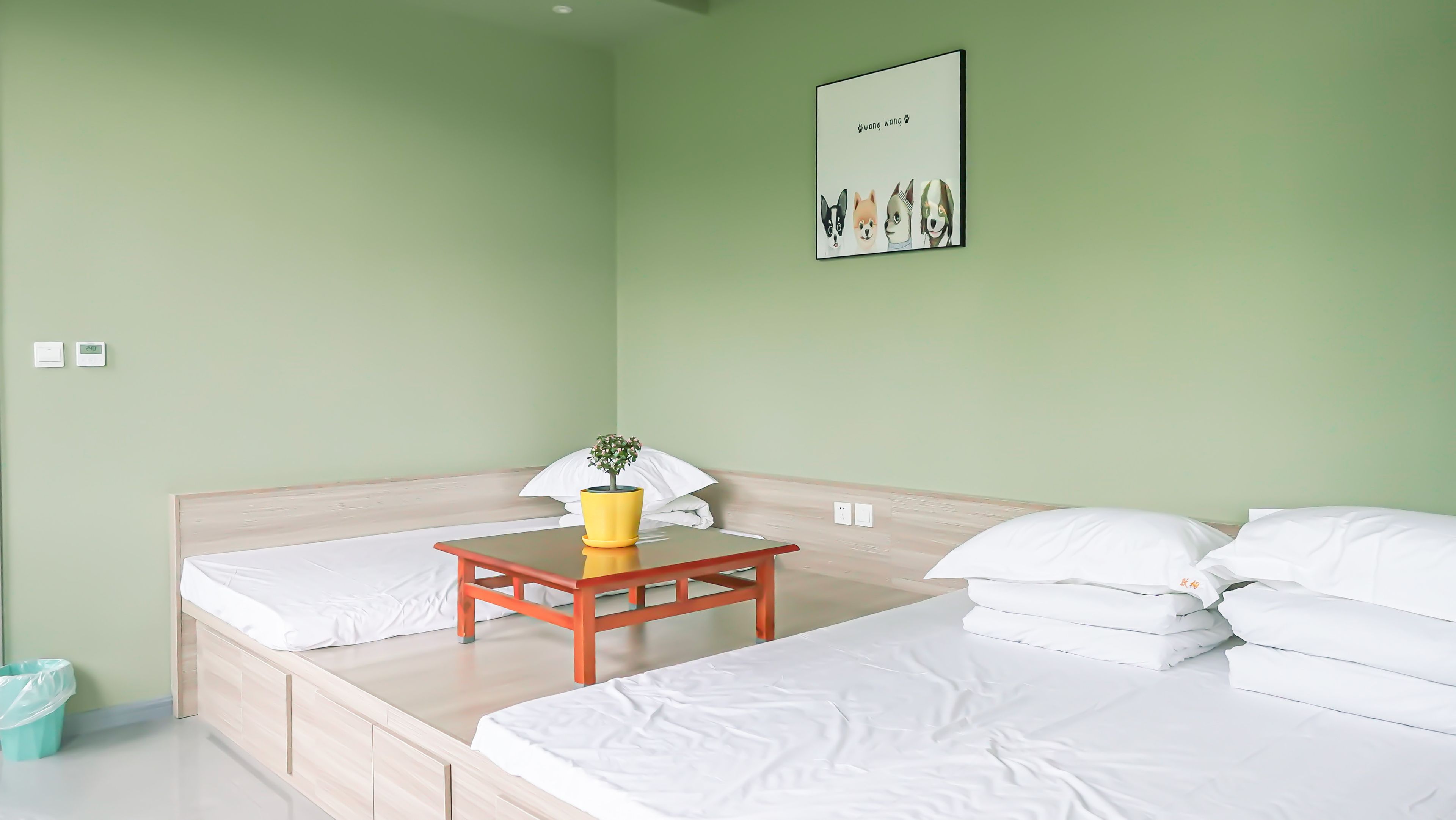 Quarto com uma cama, uma mesinha com uma planta e um quadro pendurado na parede.