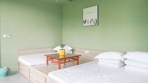 Quarto com uma cama, uma mesinha com uma planta e um quadro pendurado na parede.