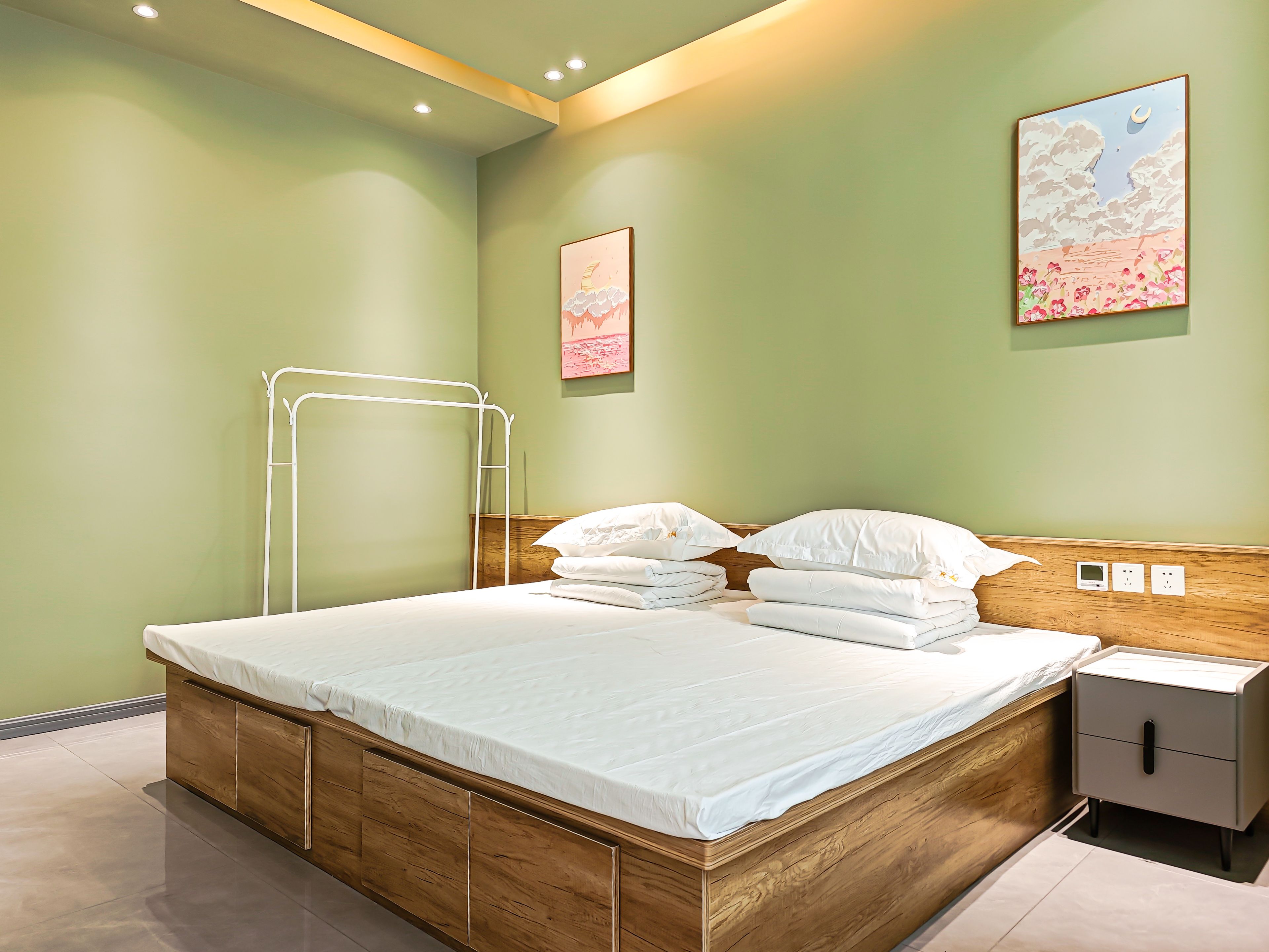 Cama bem arrumada com roupa branca, cabeceira de madeira e mesa de cabeceira com gaveta.