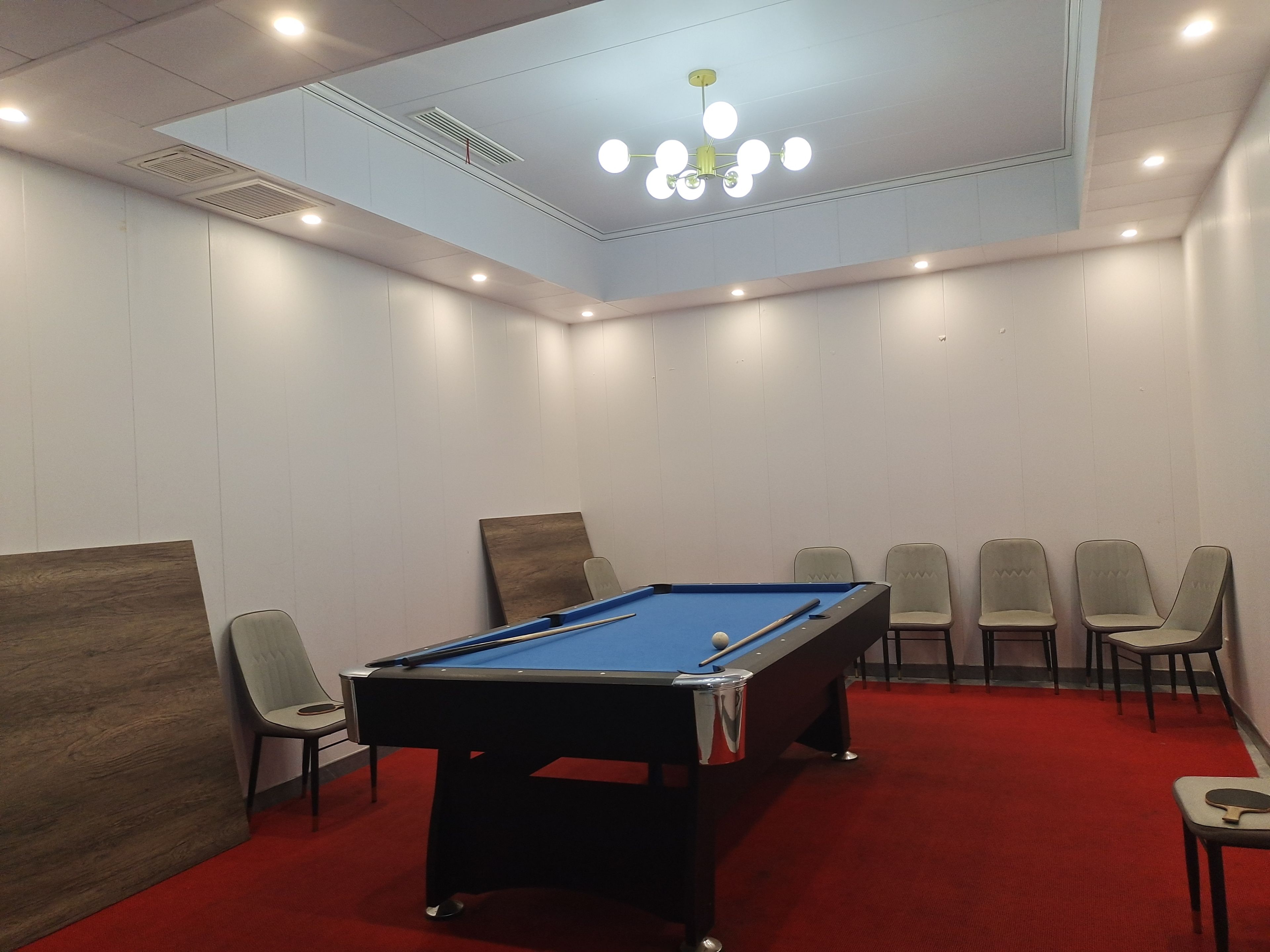 Quarto com mesa de bilhar, cadeiras e tapete vermelho.