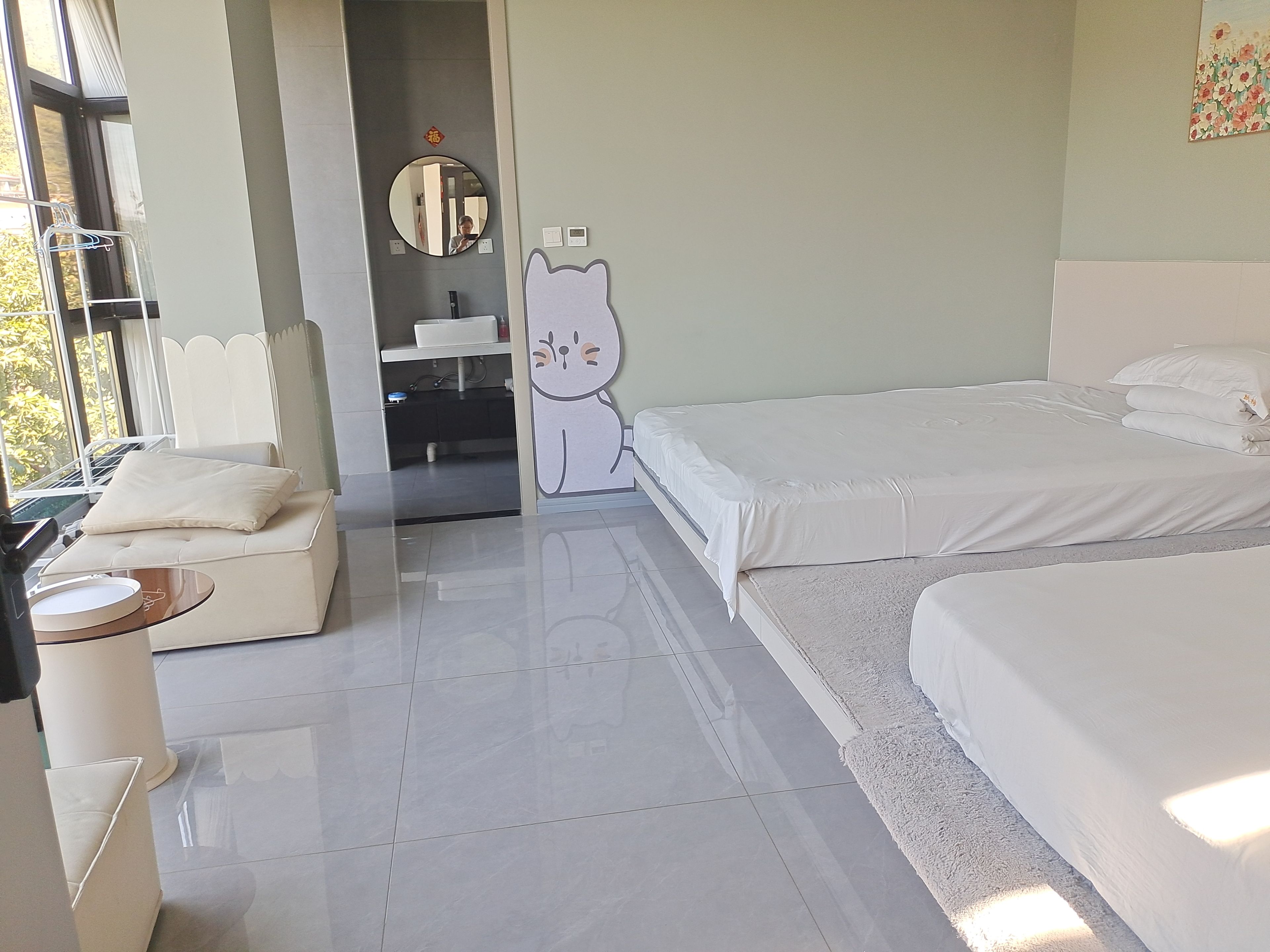 Quarto de hotel com cama, sofá, mesa pequena, espelho e um ornamento na parede.