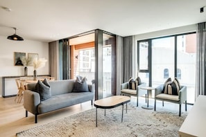 Uma sala de estar moderna com sofá, poltronas, mesa de centro e um espaço de jantar com cadeiras.