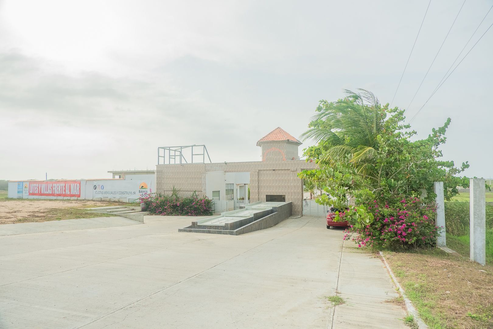 Um edifício com uma pequena torre, entrada pavimentada e uma placa.