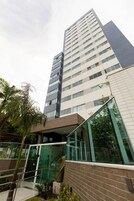 Um edifício alto com design arquitetônico moderno, com fachada de vidro e base de tijolos.