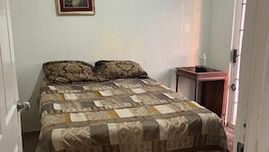 Quarto com cama, mesa de cabeceira e porta.