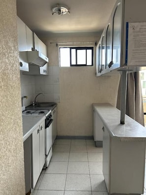 Cozinha compacta com fogão a gás, forno e geladeira pequena.