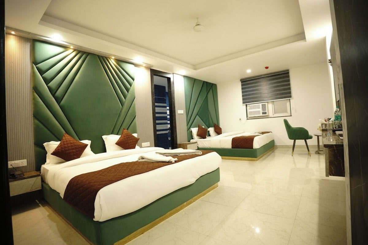 Quarto de hotel com duas camas, área de estar e pequena cozinha.