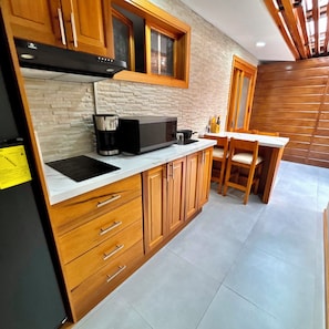 Cozinha com armários de madeira, micro-ondas, cafeteira e área de refeições com mesa e cadeiras.